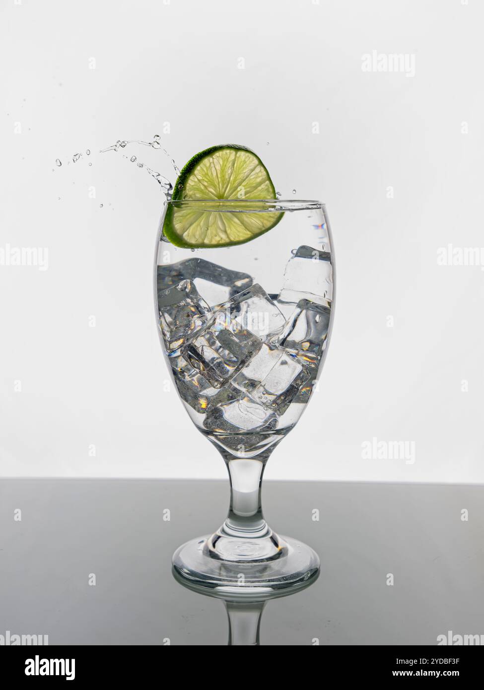 A studio concept photo of dropping a slice of lime into a water glass making a splash Stock ...