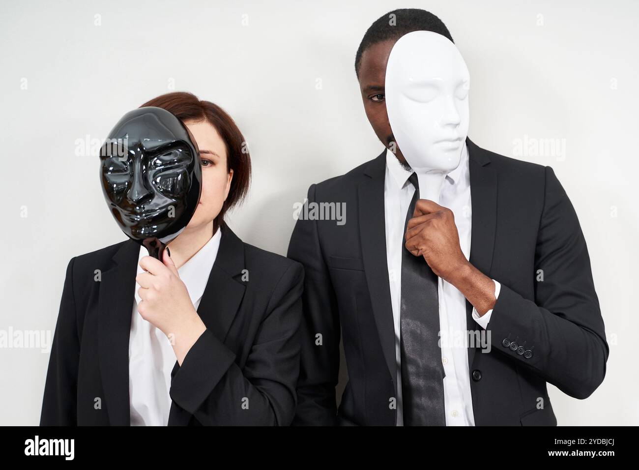 African man and Caucasian woman wearing black suits hiding face with ...