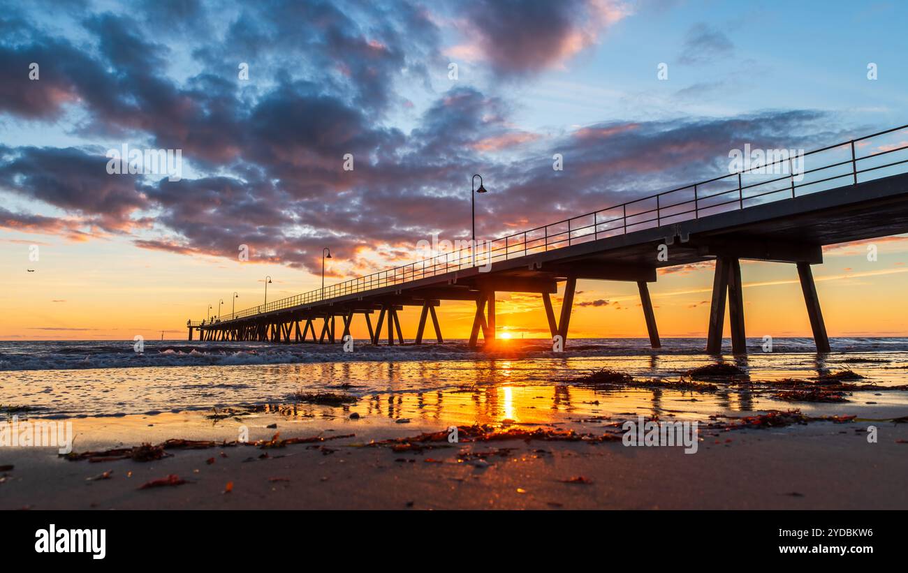 Glenelg jetty with people silhouettes standing still whicle sun dips ...