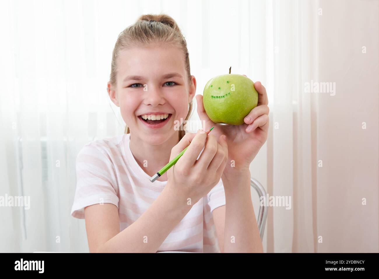 Girl having fun with green apple while doing homework, joy concept ...