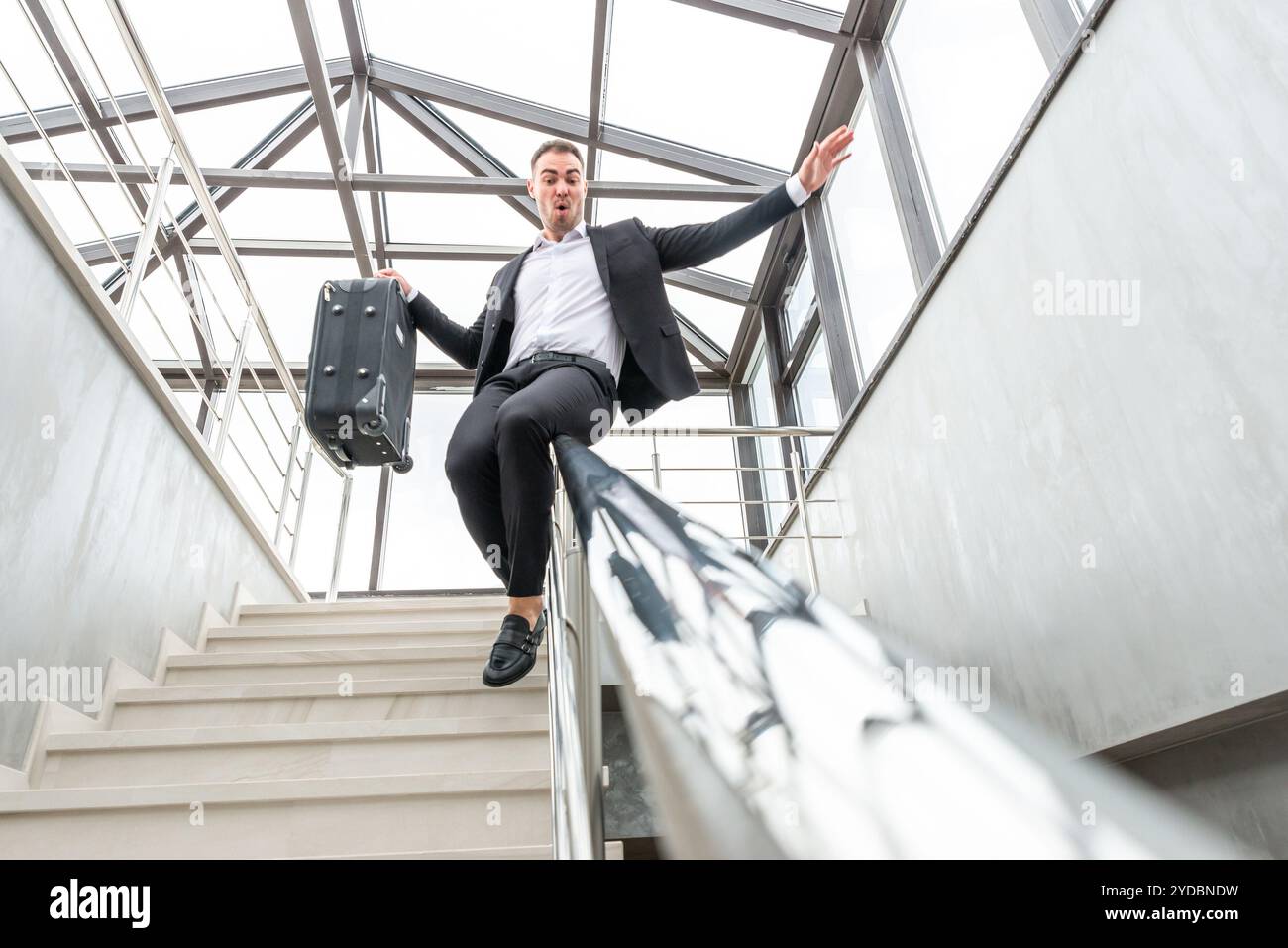 Happy businessman wearing formal suit sliding on stairs Railing in ...