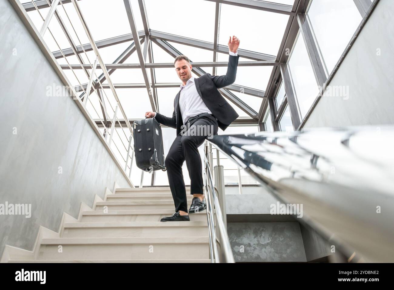 Happy businessman wearing formal suit sliding on stairs Railing in ...