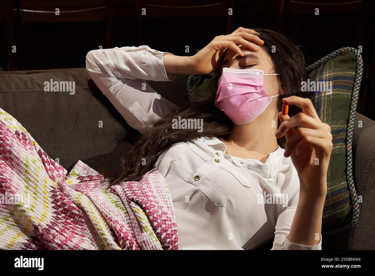 Young woman on sofa covered with a blanket freezing blowing running ...