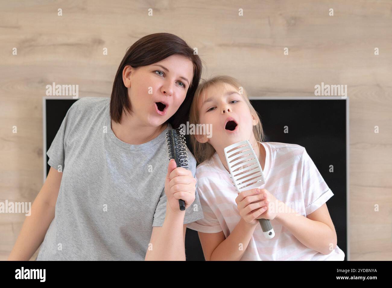 Happy family young adult mother and cute teen daughter having fun singing karaoke song in ...