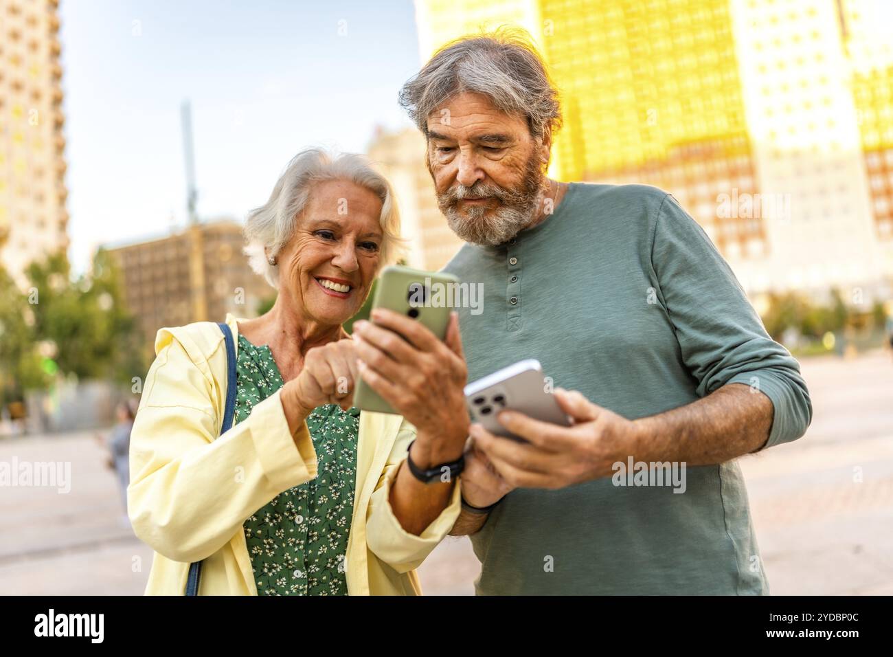 Senior smiling woman showing mobile screen to senior partner outdoors ...