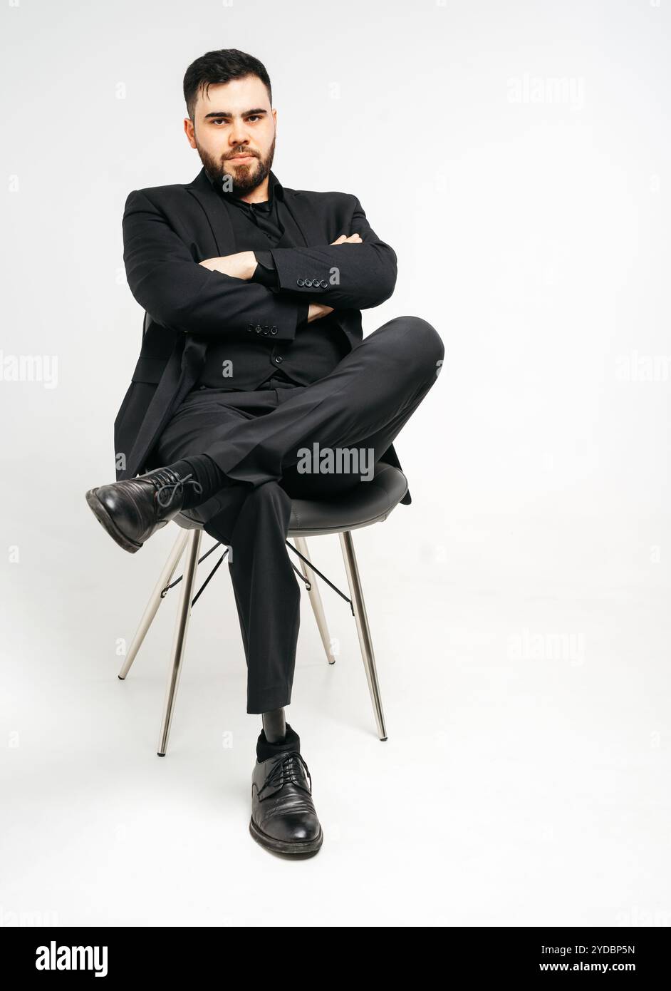 Disabled young man with prosthetic leg sitting on a chair in studio ...