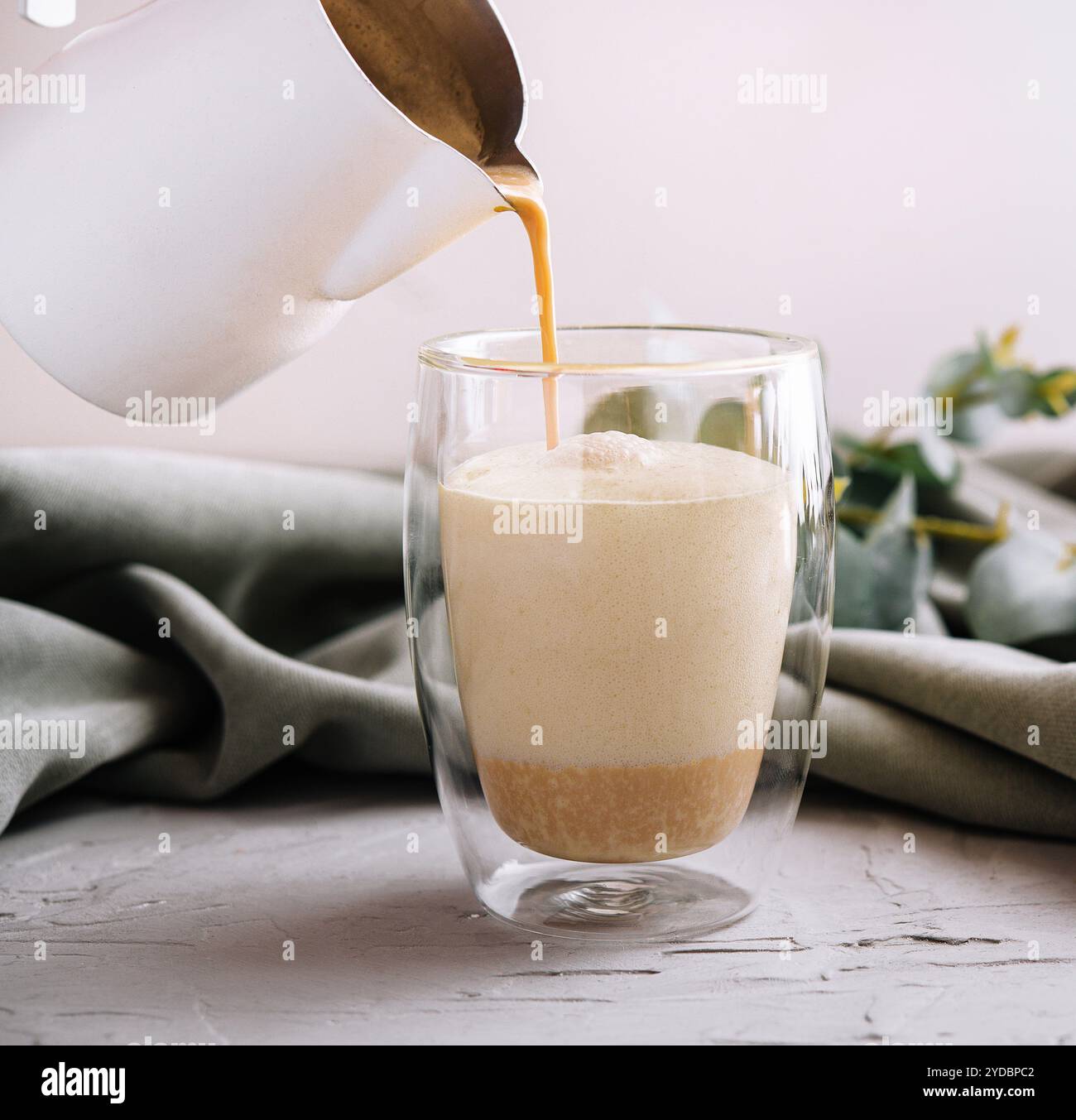 pouring a coffee with milk from teapot to glass cup Stock Photo - Alamy