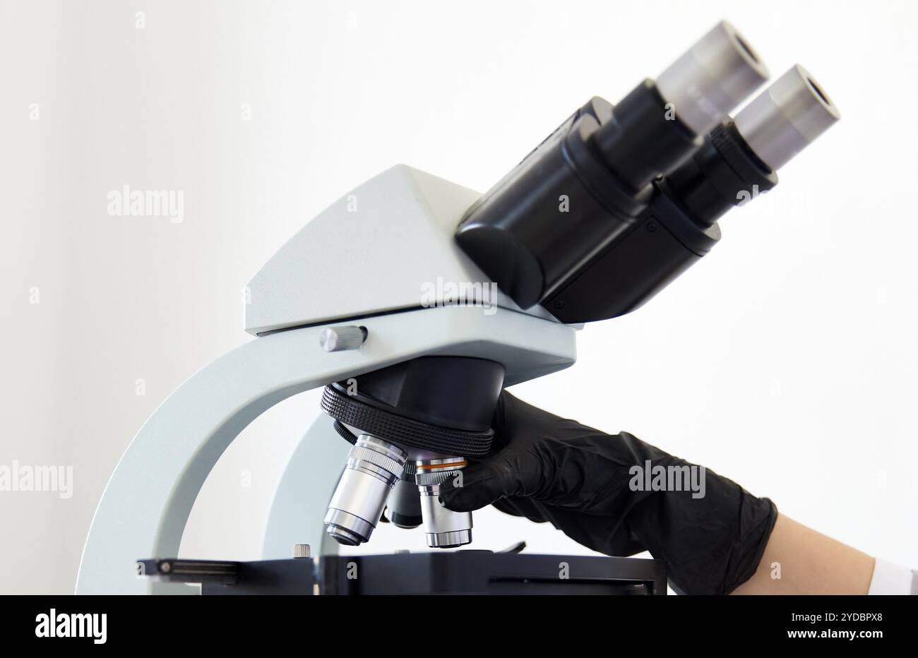 Closeup of microscope and hands wearing rubber gloves in modern ...