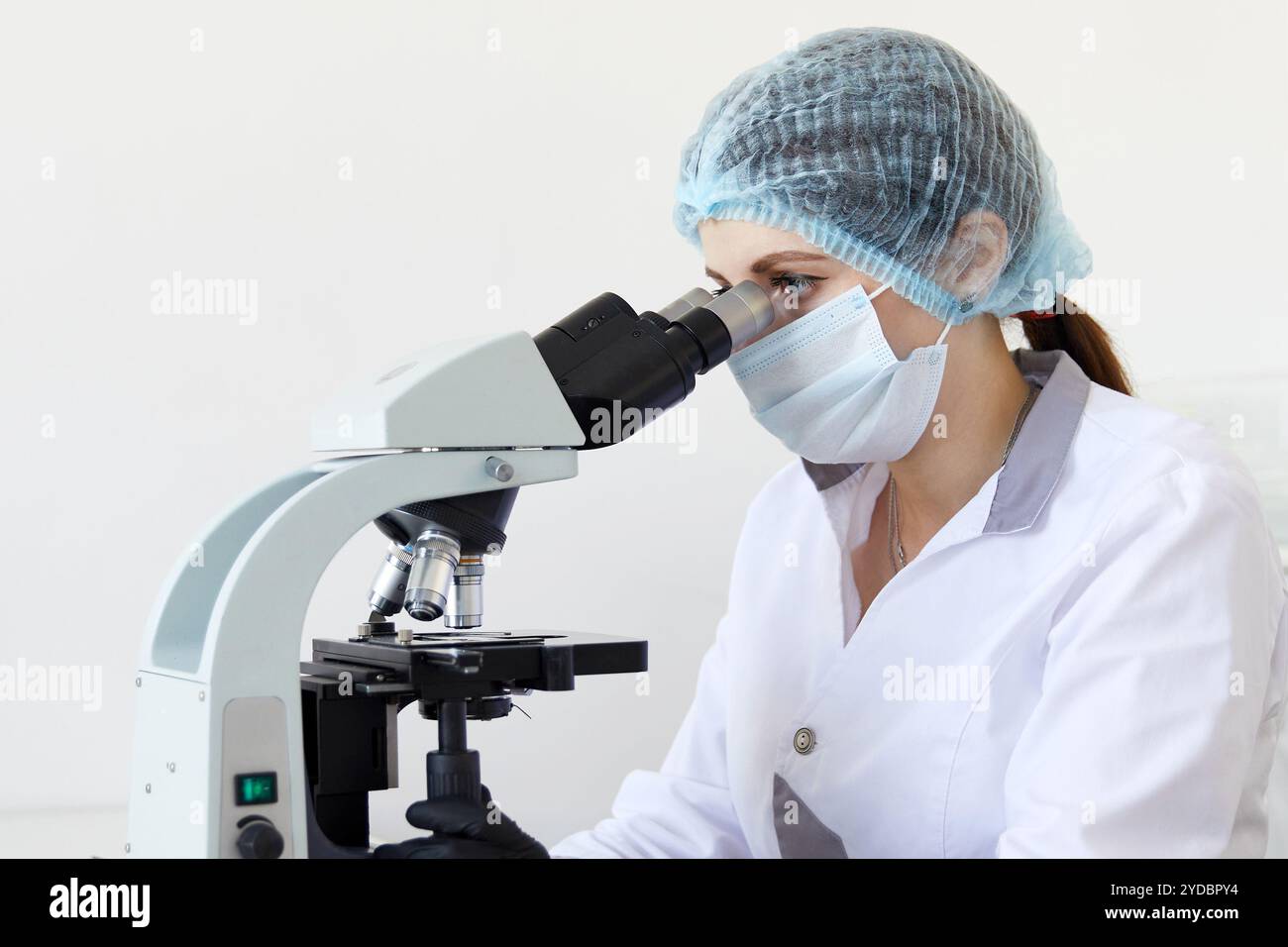 Female scientist looking through microscope in modern chemical laboratory doing some research ...
