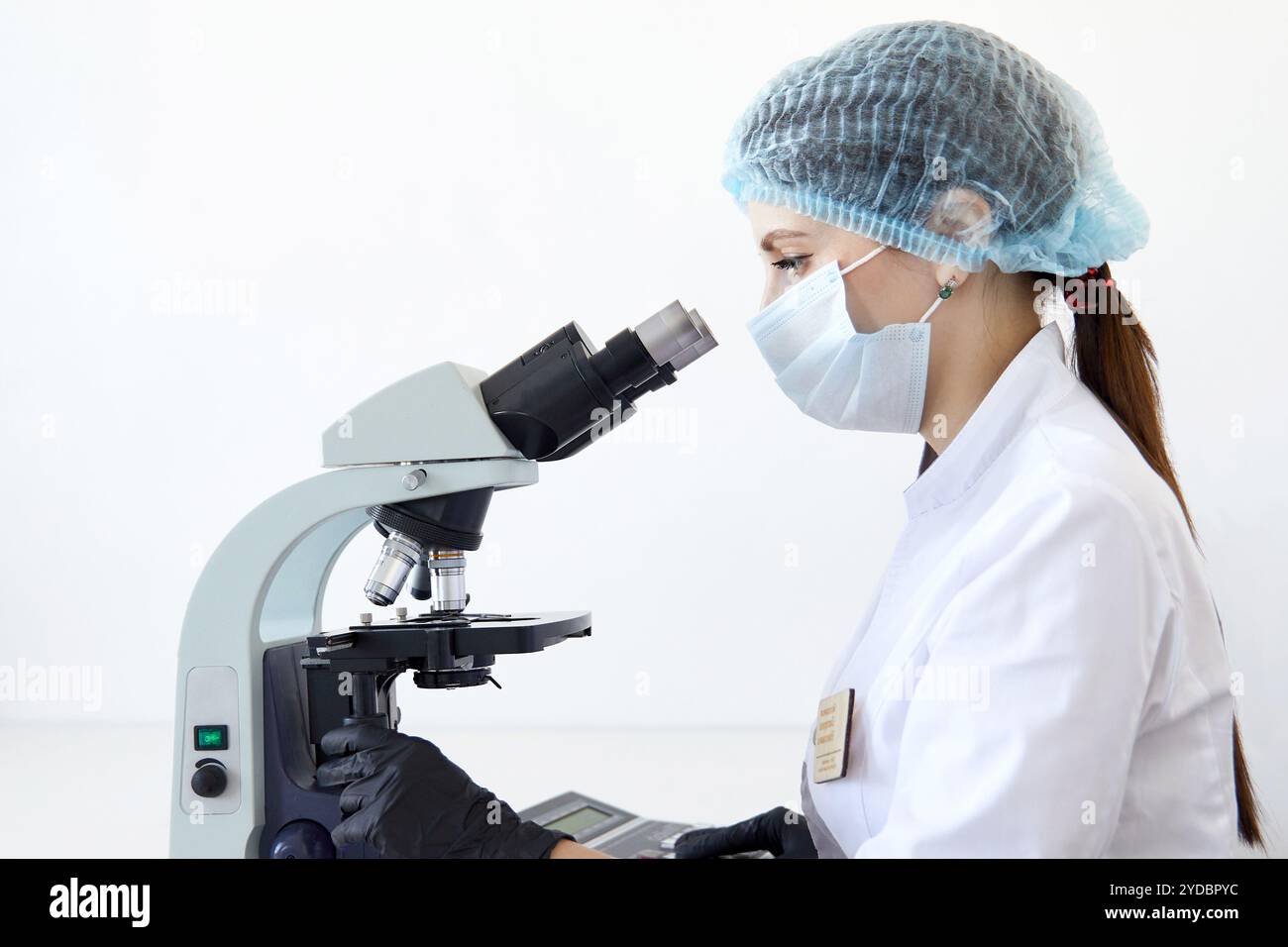 Female scientist looking through microscope in modern chemical laboratory doing some research ...