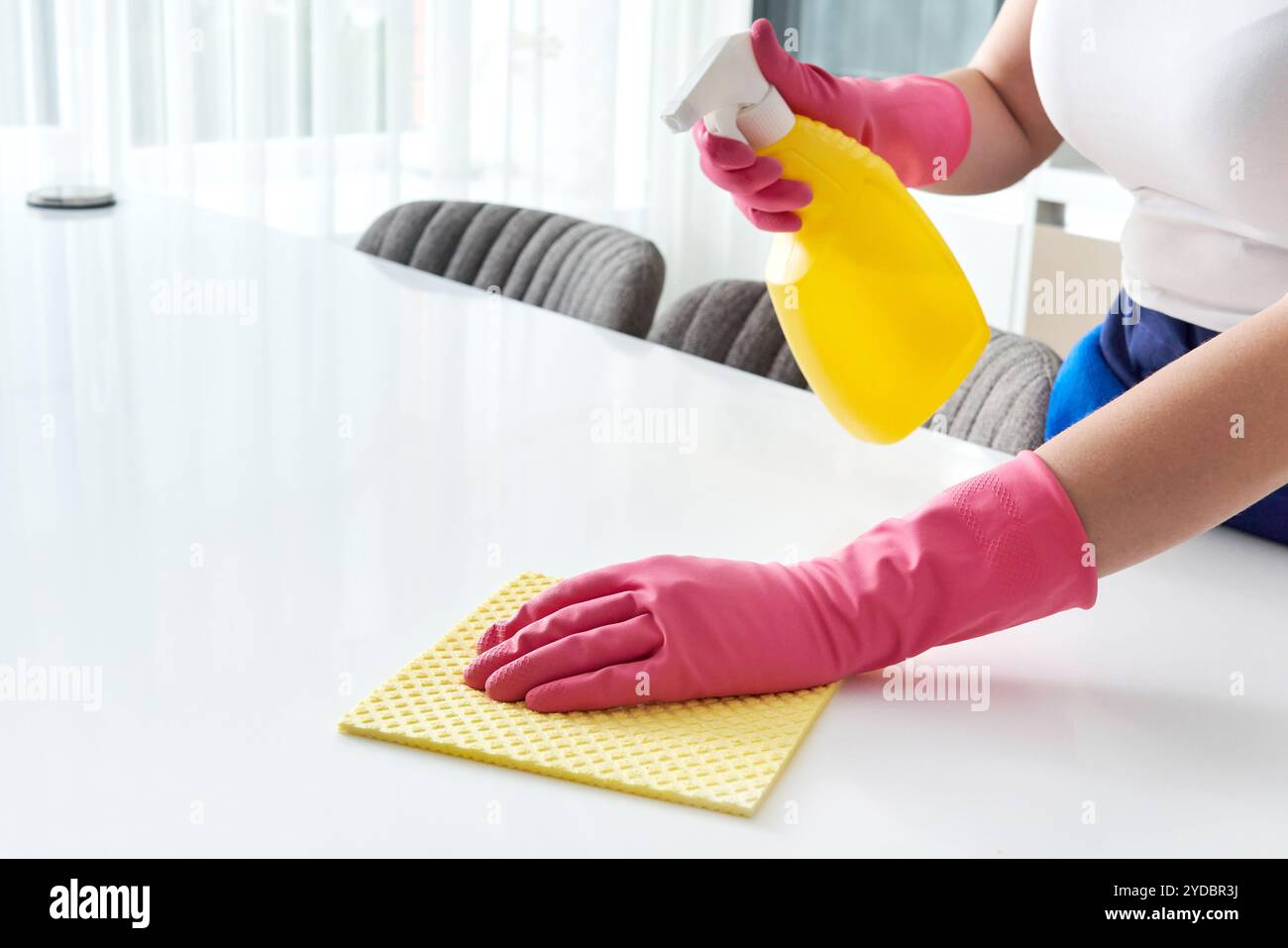 Woman wearing rubber gloves cleaning table with cloth. Disinfecting a ...