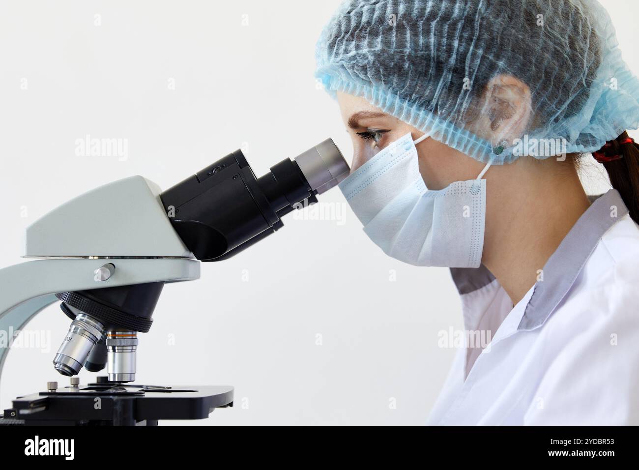 Female scientist looking through microscope in modern chemical laboratory doing some research ...