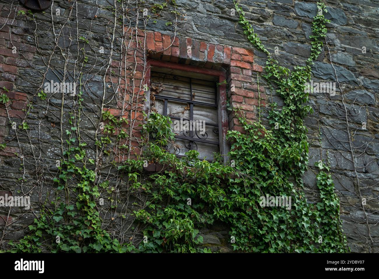 The wall of an abandoned, industrial building shows crumbling stone and ...