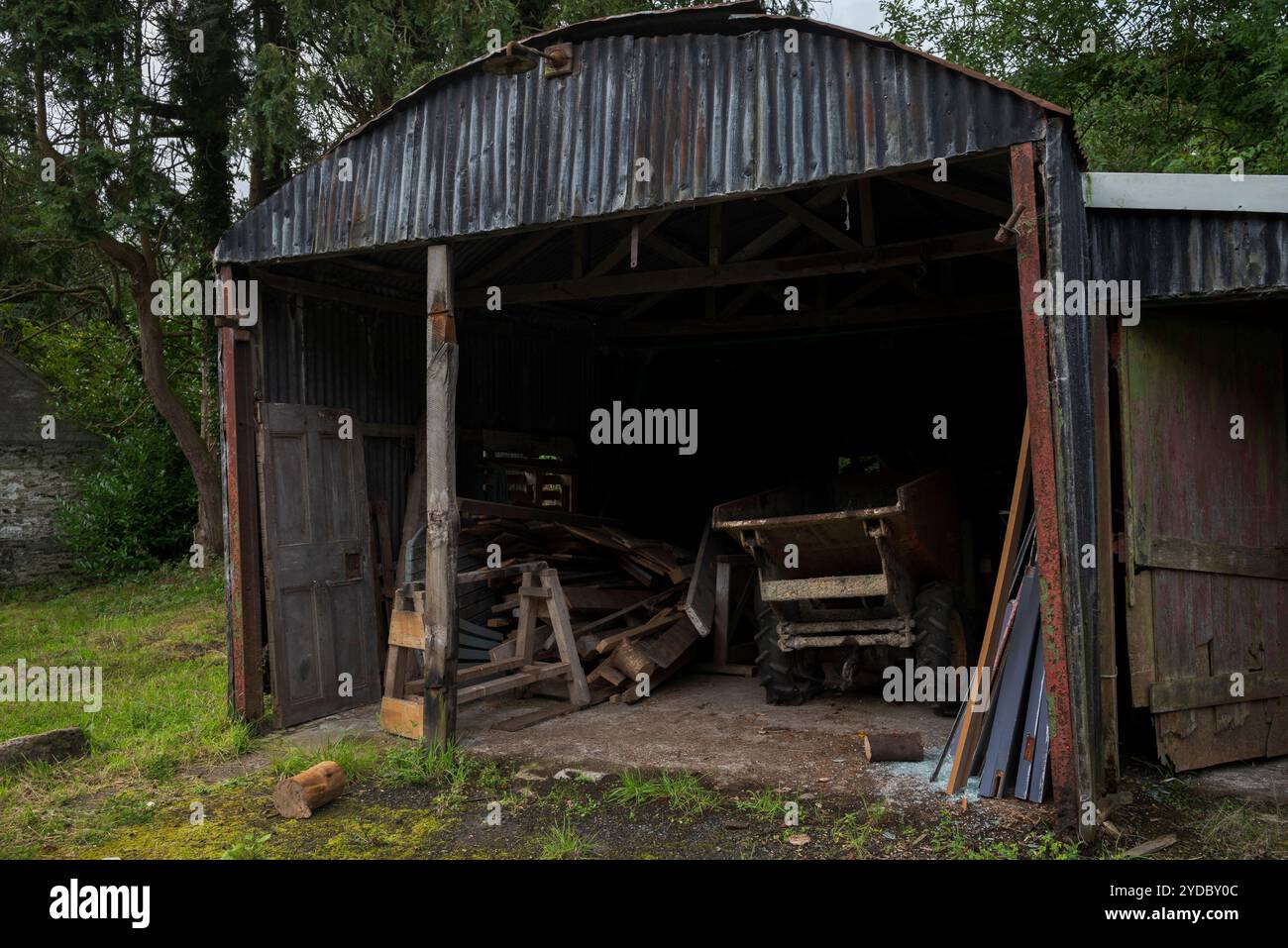 Inside the dark, neglected shed, disordered wooden planks and a dumper ...