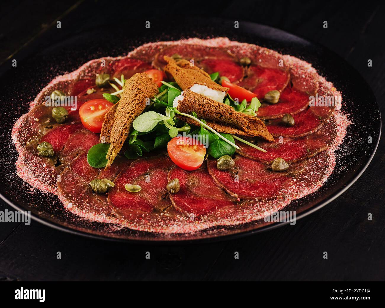 Beef carpaccio with capers on black plate Stock Photo - Alamy