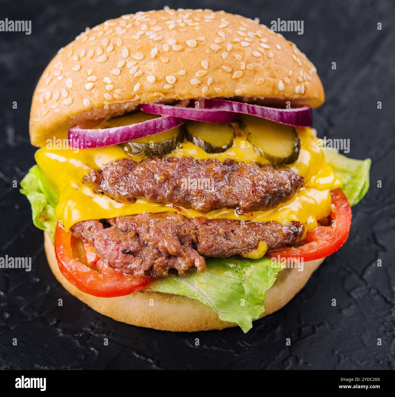 Double patty burger with pickles on black stone Stock Photo - Alamy