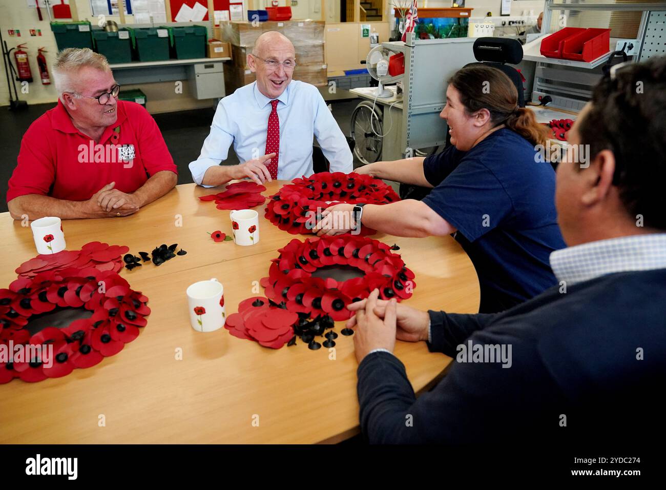 Defence Secretary John Healey (second left) makes a wreath with ...