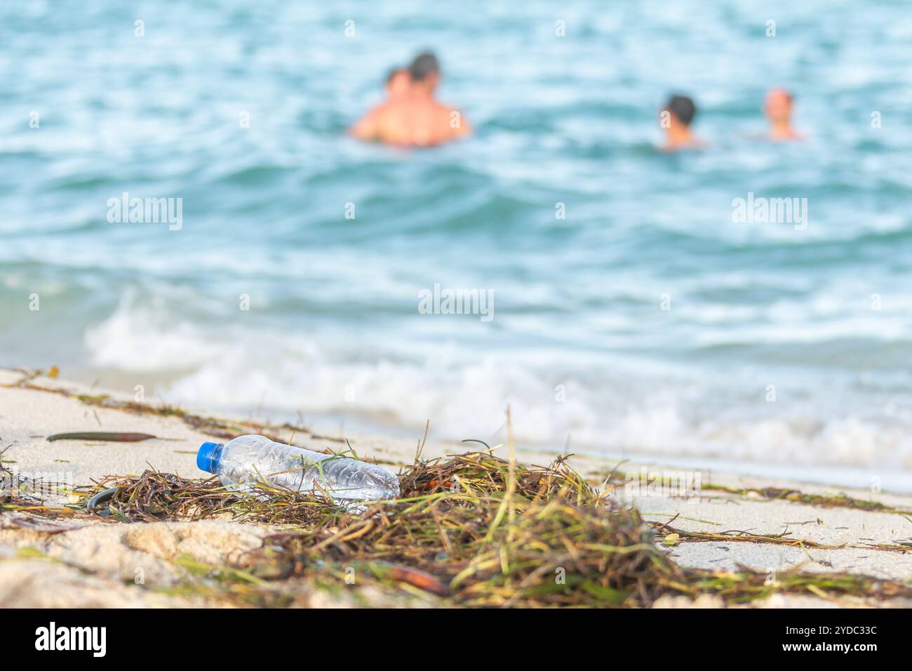 Close up image of empty plastic water bottle on dirty beach filled with ...