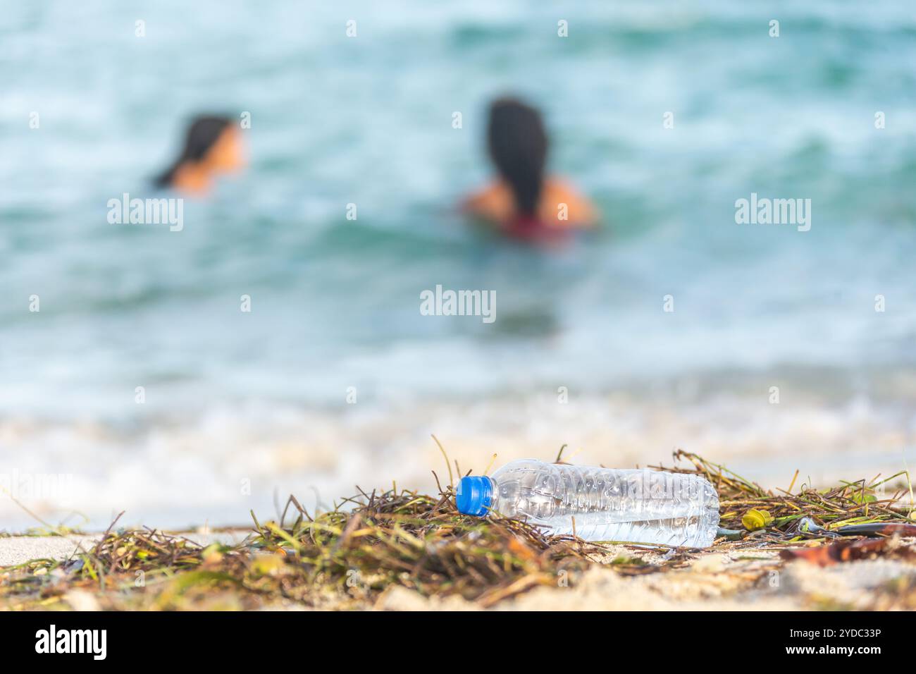 Close up image of empty plastic water bottle on dirty beach filled with ...