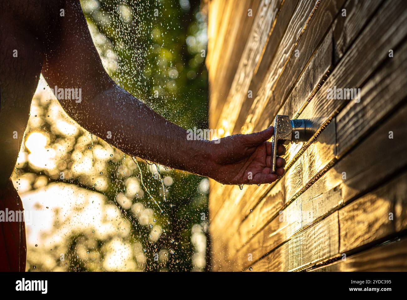 Man opens outdoor shower faucet at sunset. Concept of summer rest and ...
