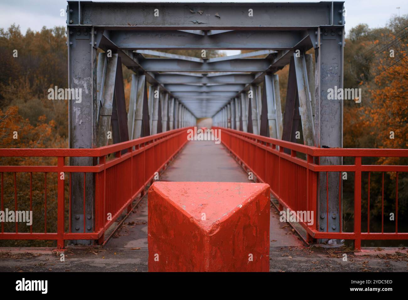 Pedestrian bridge over the river made of iron beams and with a red ...