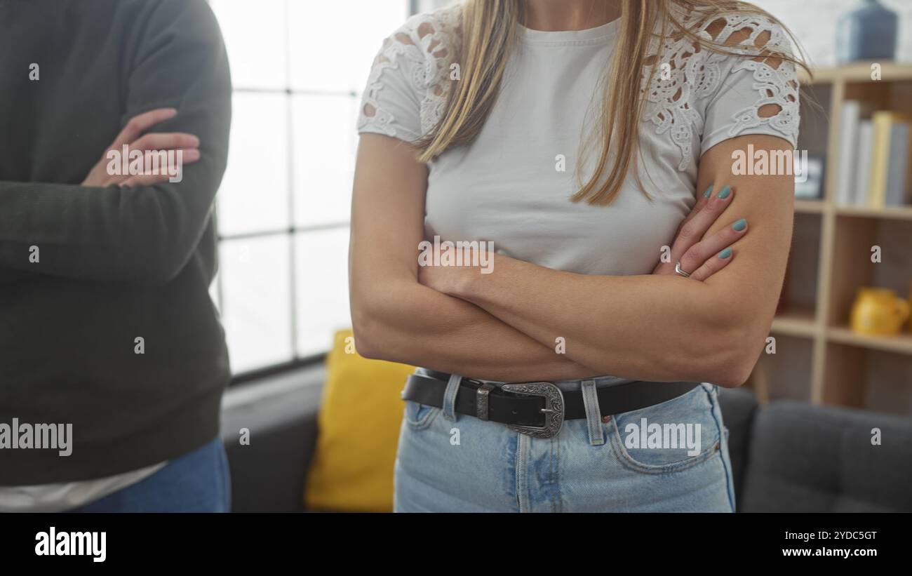 A man and a woman standing with arms crossed in a modern living room ...
