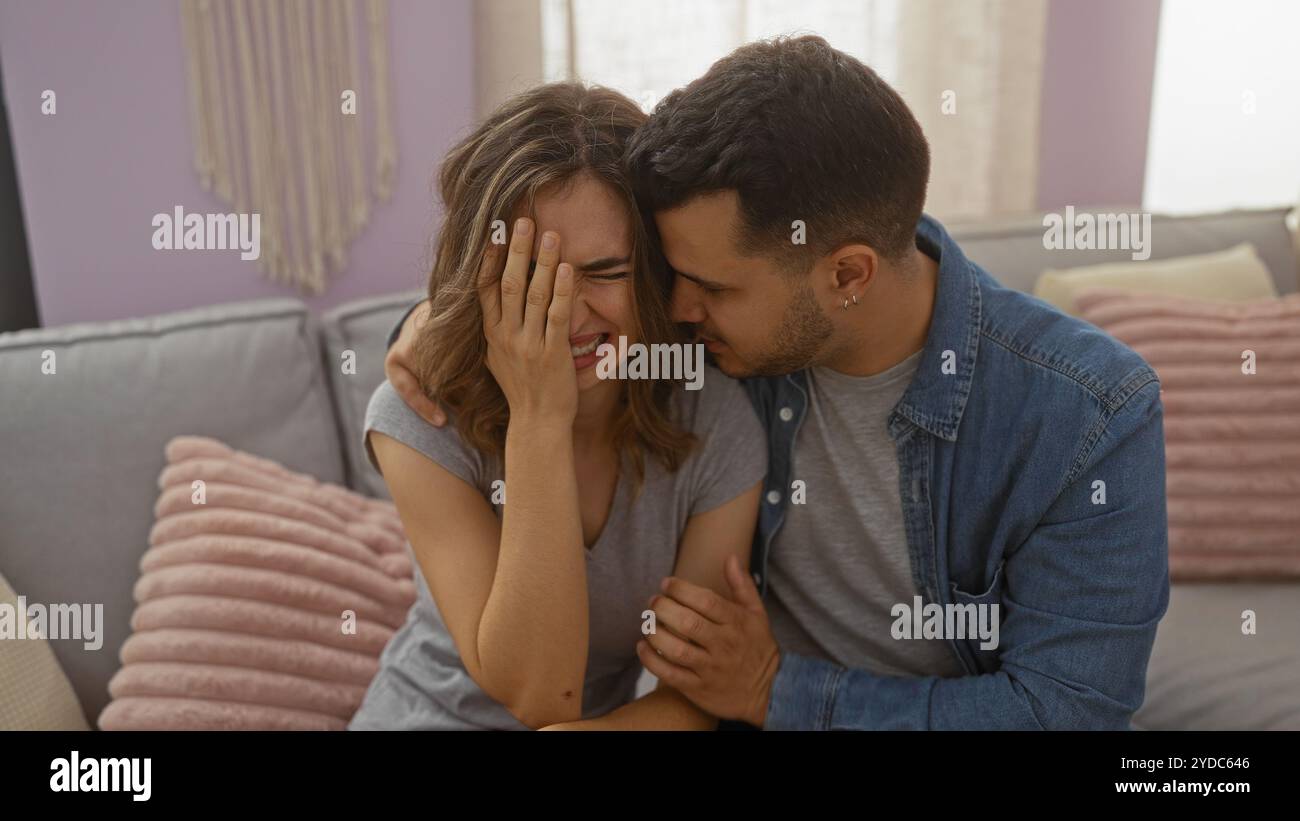 Woman crying in living room while man comforts her on sofa in cozy home ...
