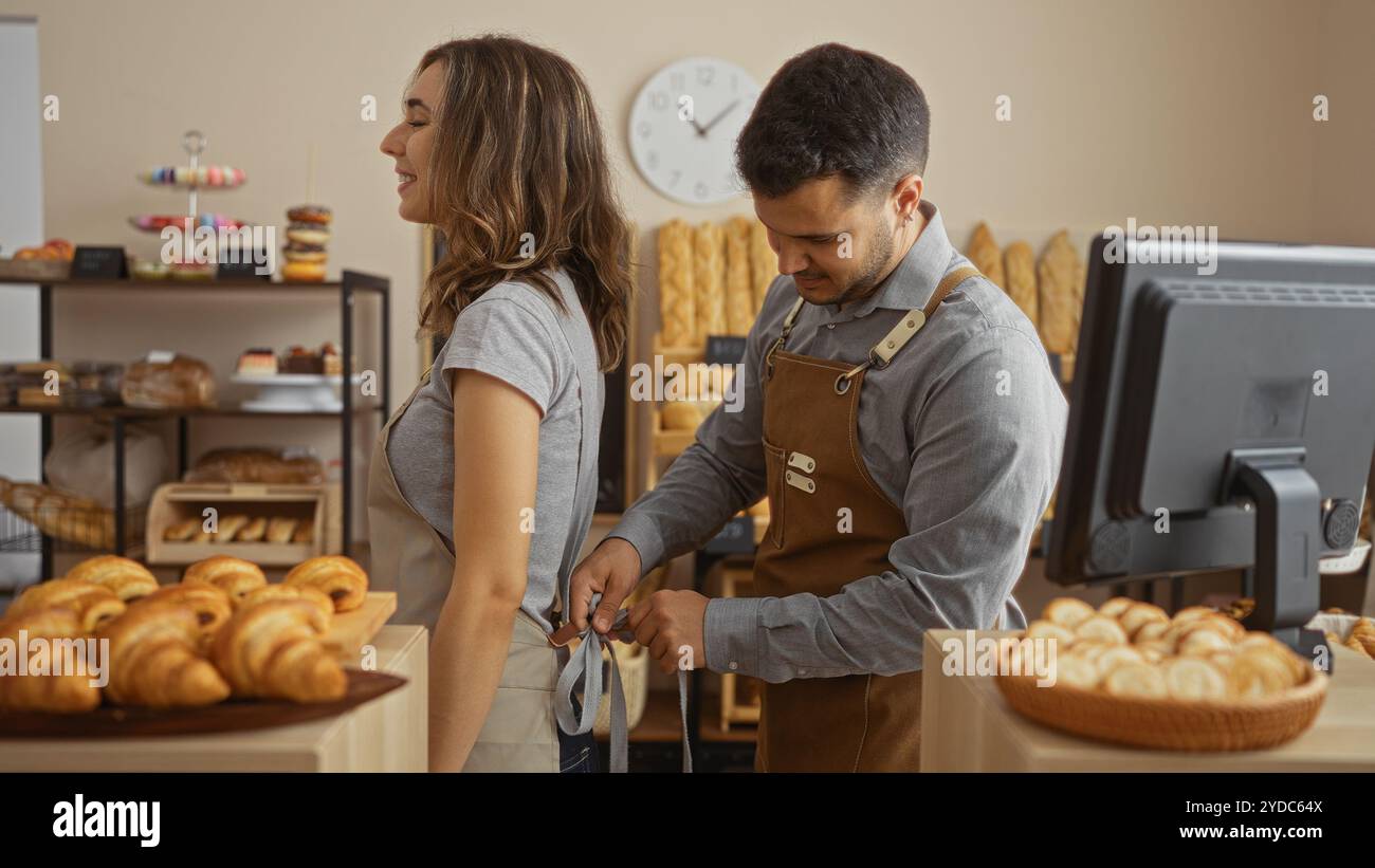 Man tying apron on woman in bakery with various pastries and bread in background Stock Photo - Alamy