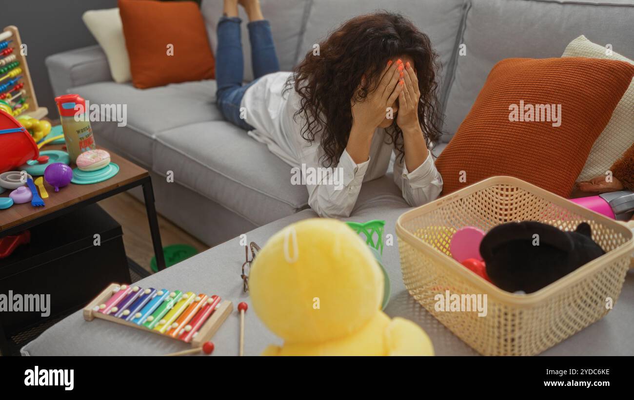 Woman overwhelmed by toys in a messy living room, covering her face in ...