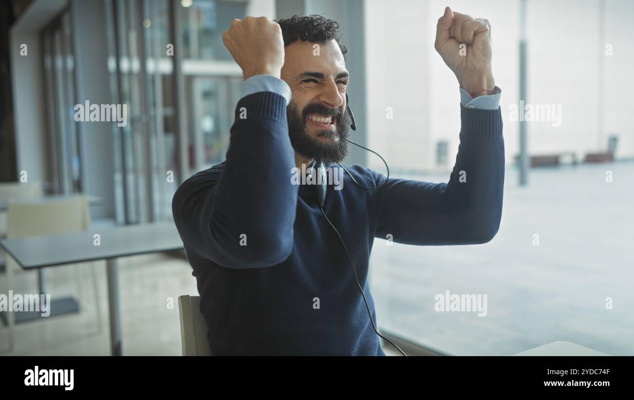 A bearded man in a modern office showing a triumph gesture, expressing ...