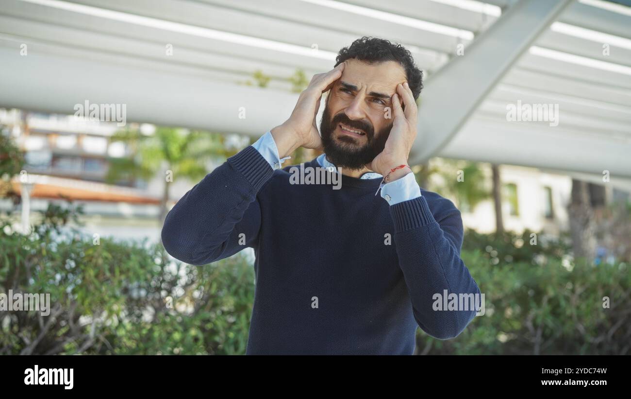A distressed middle-aged man with a beard stands outdoors in a park ...