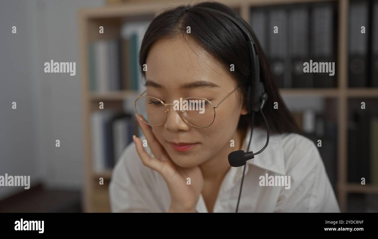 Young chinese woman wearing glasses and a headset, working indoors in ...