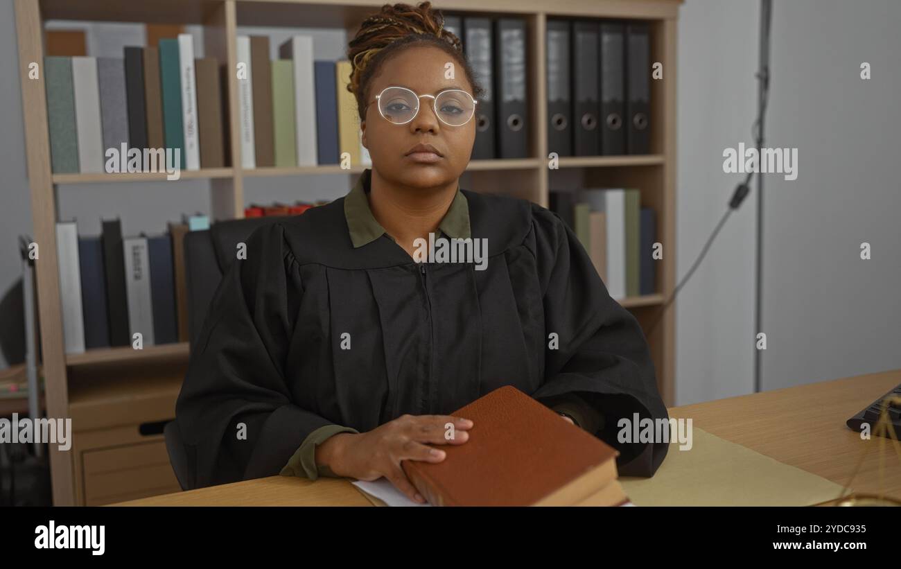 Woman sitting in judge robe at office desk with bookshelf background ...
