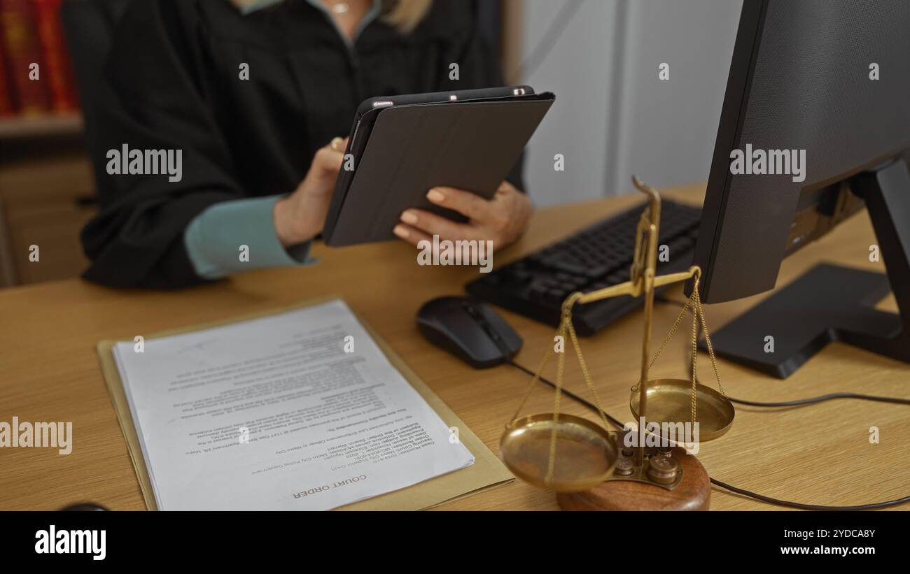 Woman using tablet at her desk in a courtroom with court documents ...