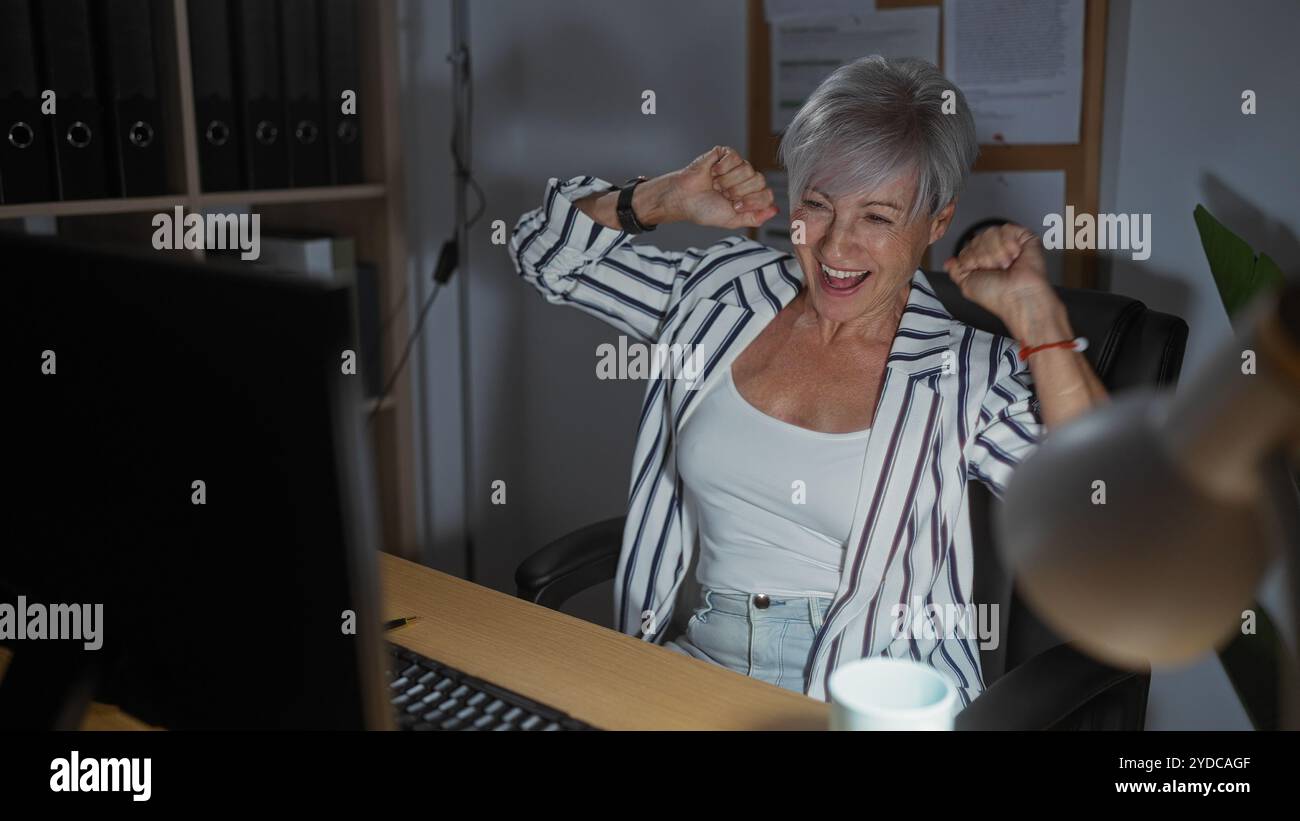 Beautiful grey-haired woman working late in an office, expressing ...