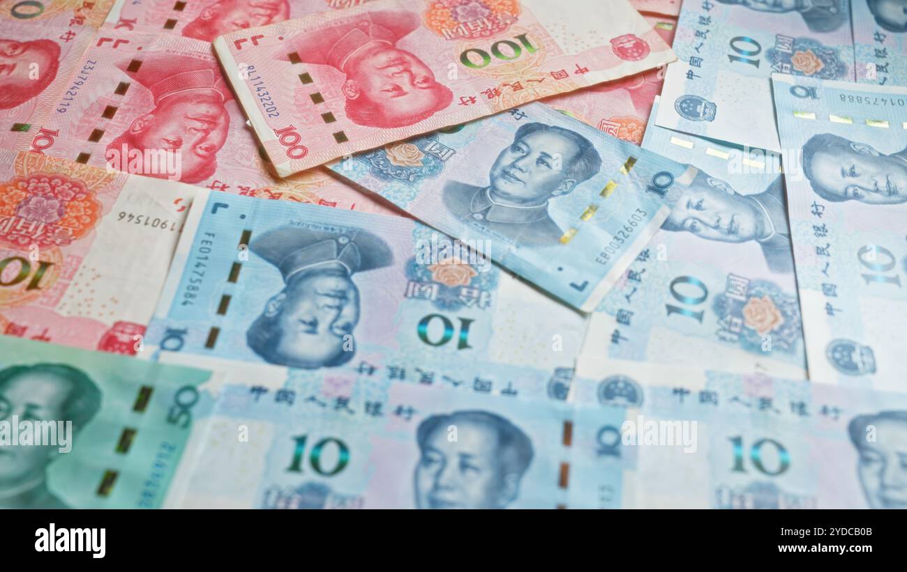Chinese yuan banknotes scattered across a surface, highlighting various ...
