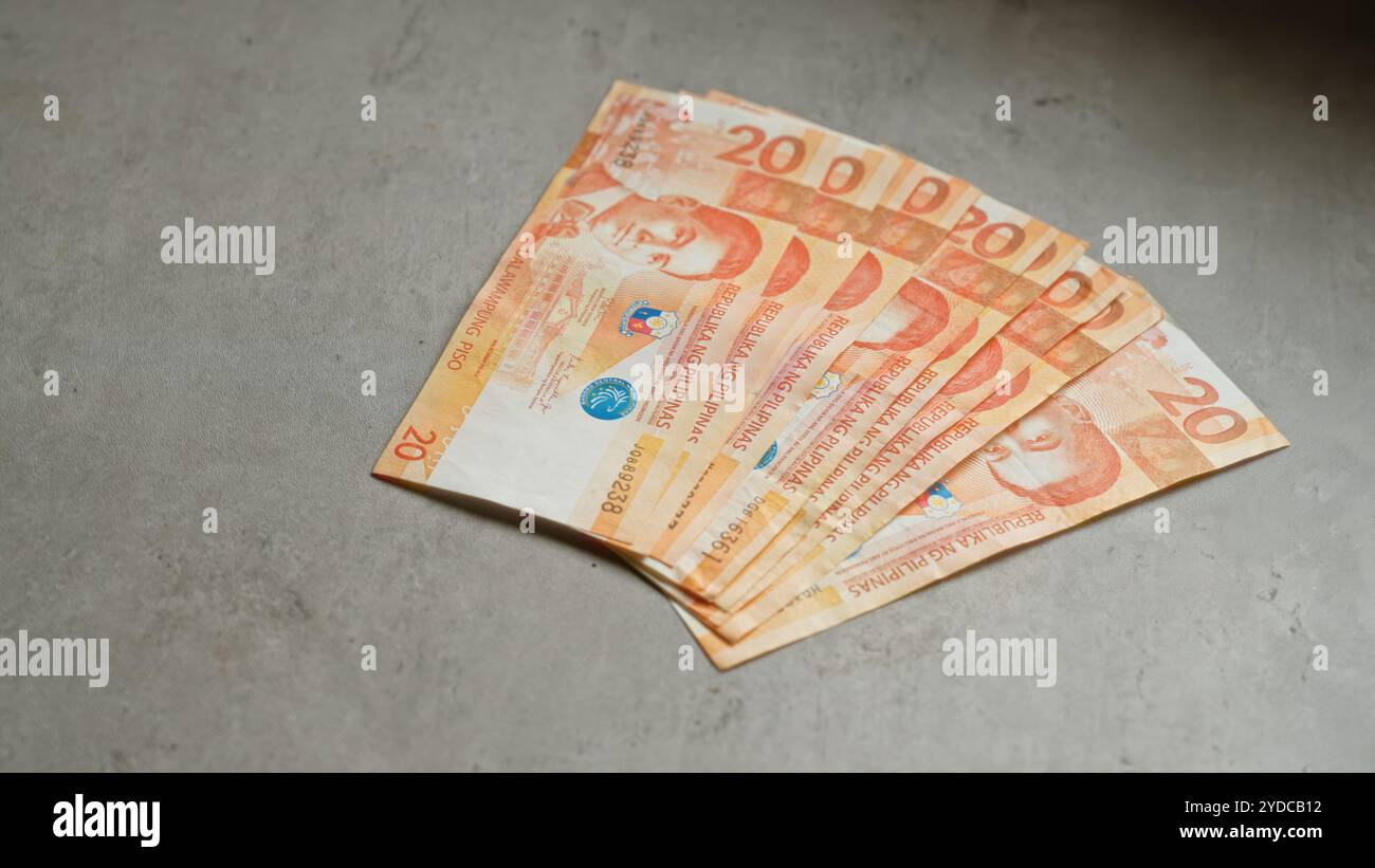 Philippine pesos banknotes spread out on a concrete surface, showcasing ...
