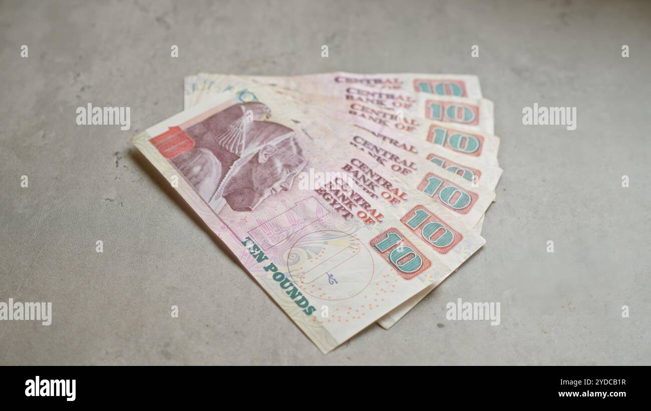 Egyptian ten-pound banknotes spread across a concrete surface ...