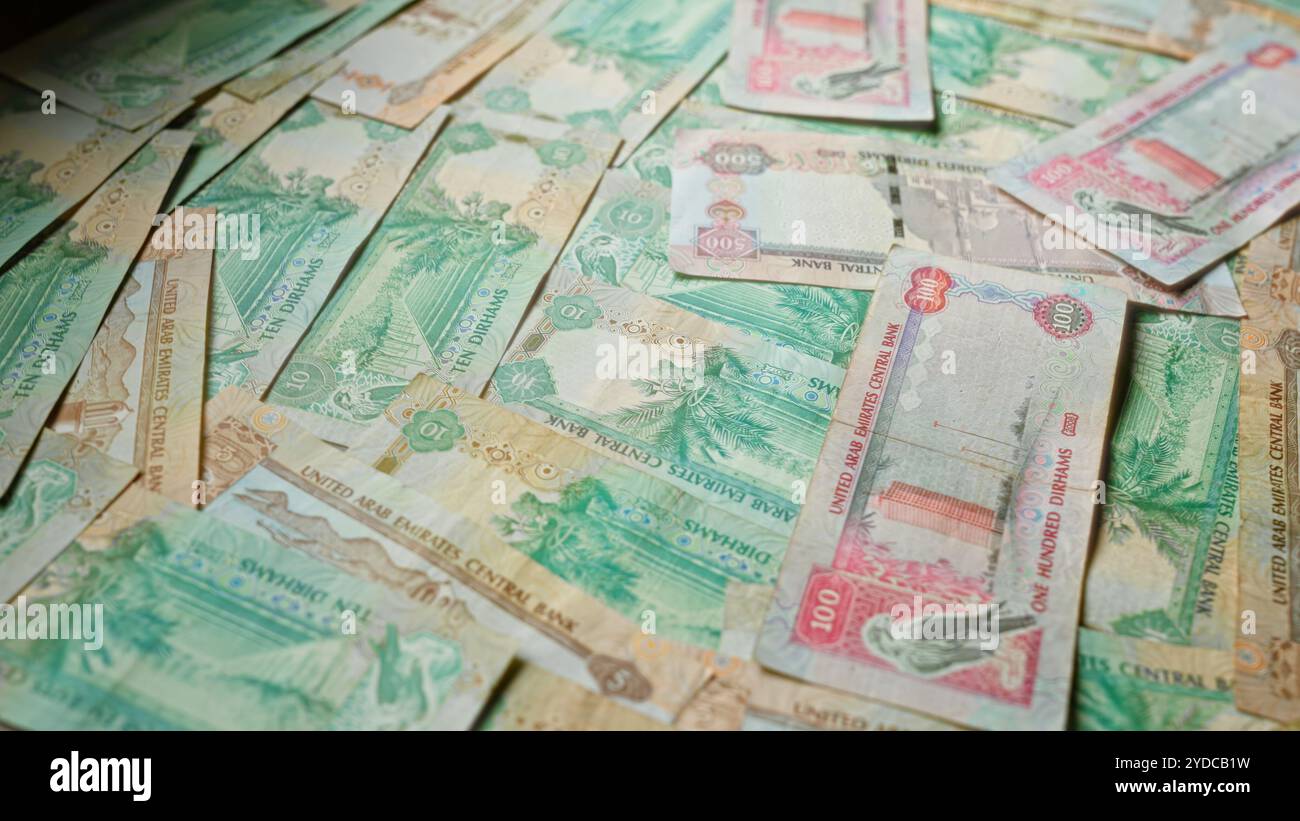 Scattered uae dirham banknotes showing various denominations of emirati ...