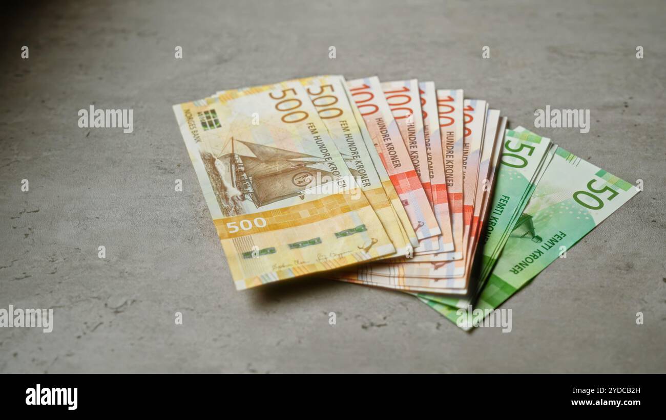 Norwegian banknotes lie fanned out on a concrete surface, showcasing ...