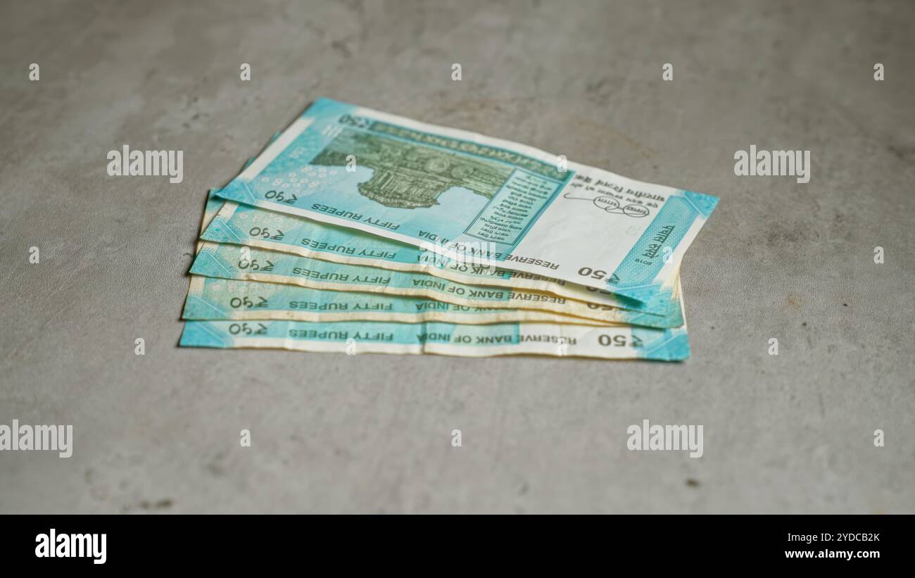 Indian fifty-rupee banknotes spread on a concrete surface, highlighting ...