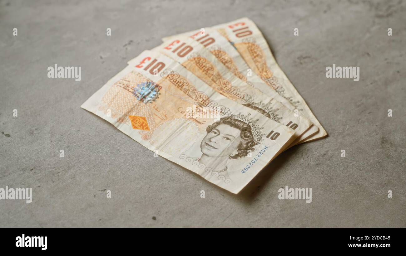 British ten-pound banknotes fanned out on a concrete surface ...