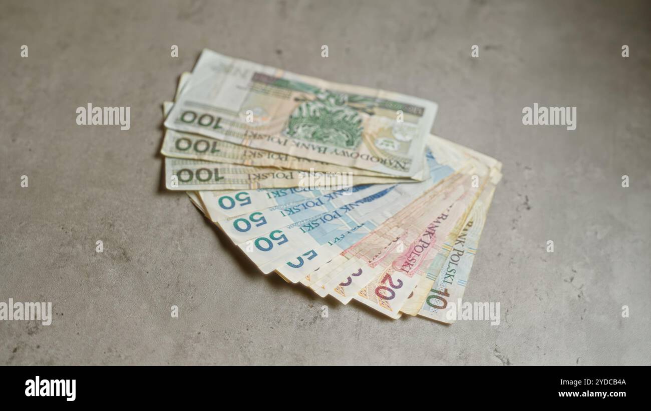Polish zloty banknotes spread on a concrete surface, showcasing various ...
