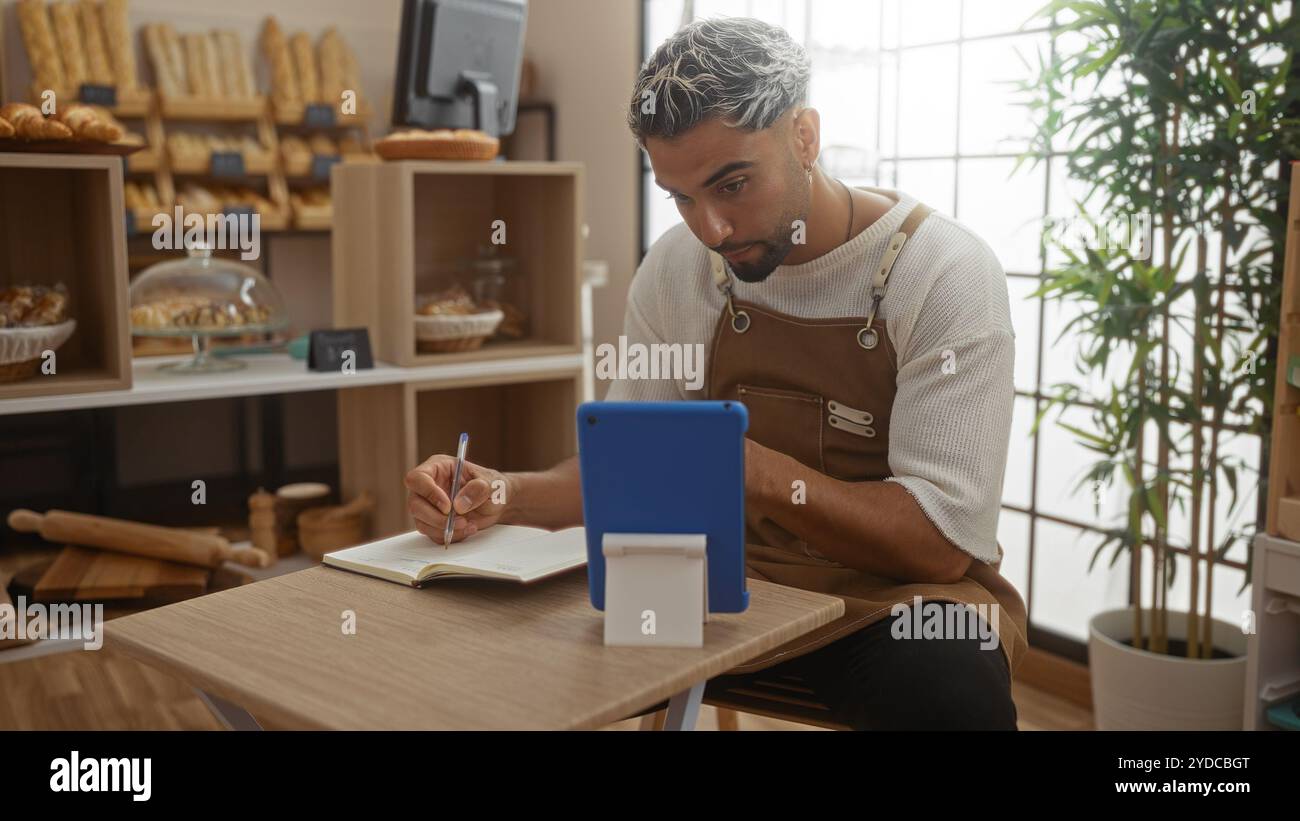 Young muslim man with a beard writing notes in a bakery cafe interior ...