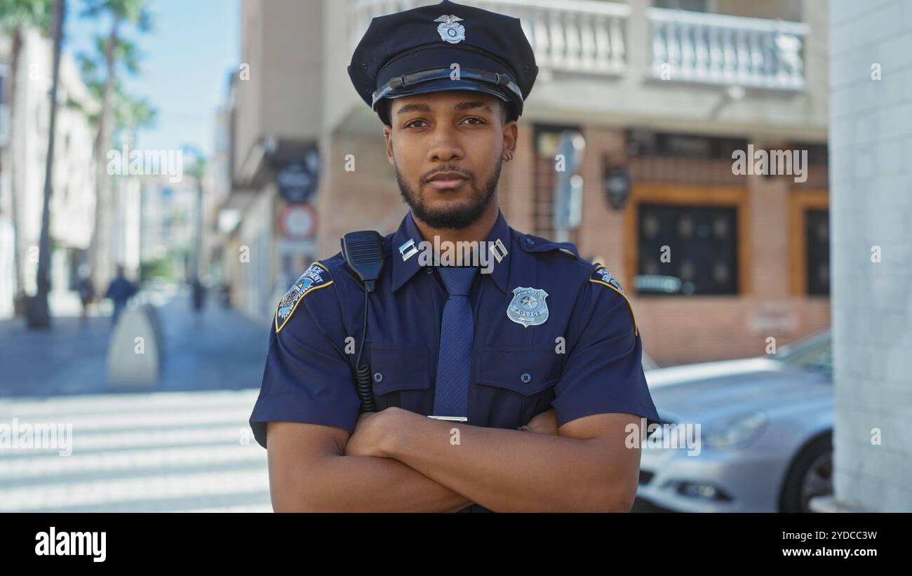 Confident african american police officer with arms crossed standing on ...