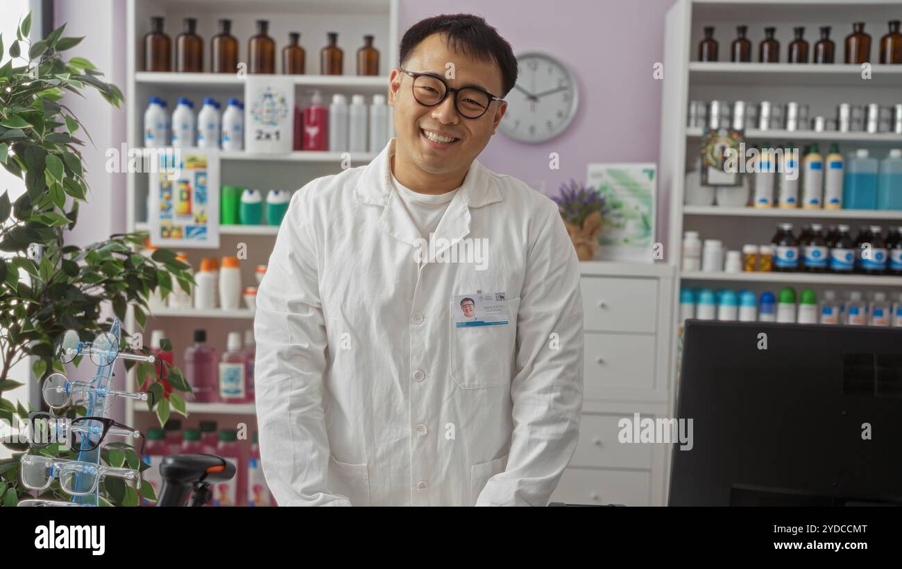 Smiling asian male pharmacist poses in a well-organized pharmacy ...