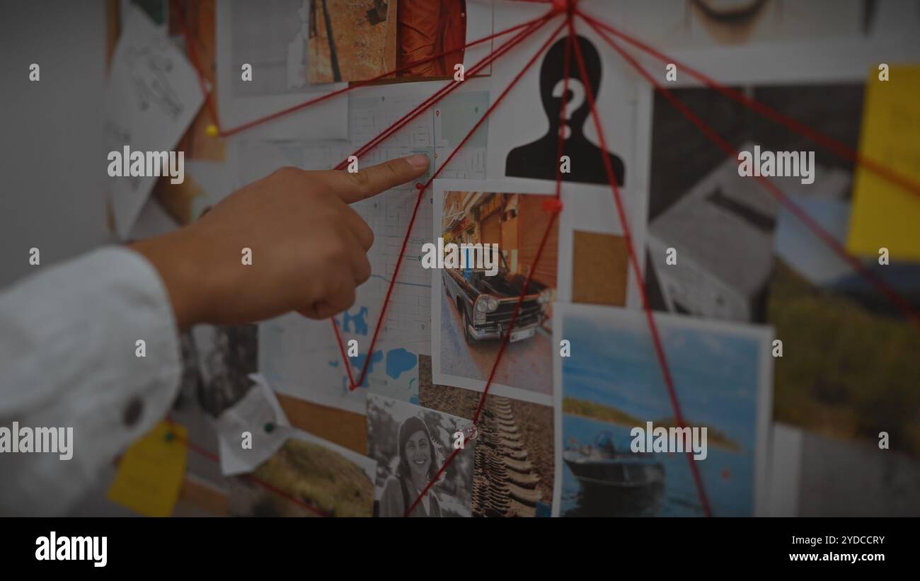 A young asian man points at a clue on a detective's evidence board in a ...