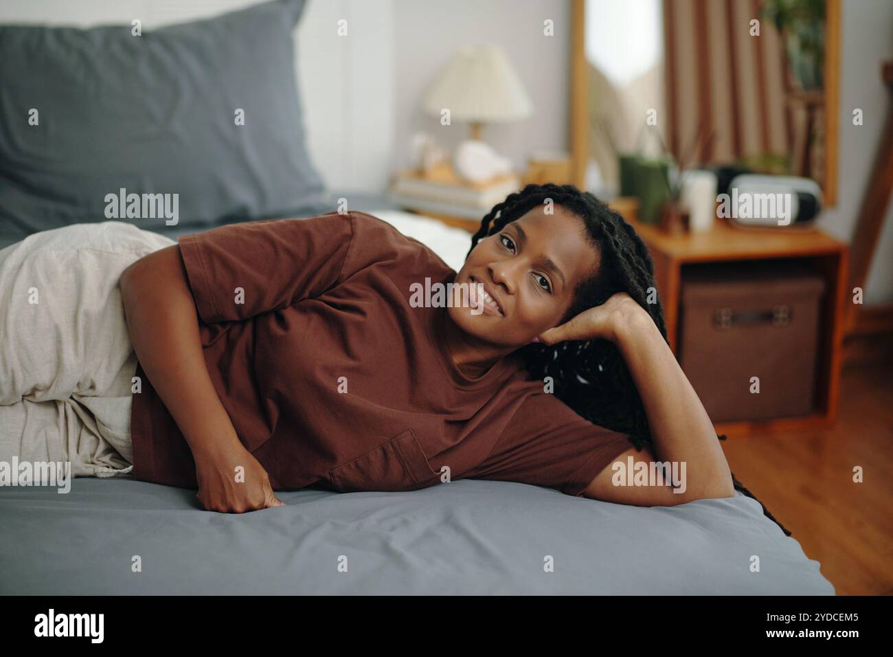 Relaxing Woman Lying Down on Comfortable Bed Smiling Stock Photo - Alamy