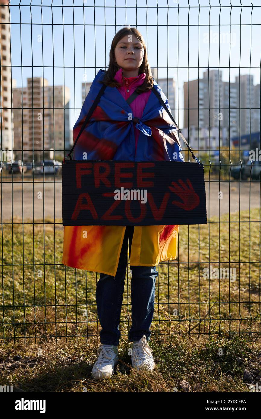 Ukrainian girl demonstrating with a sign "Free Azov" and national blue ...