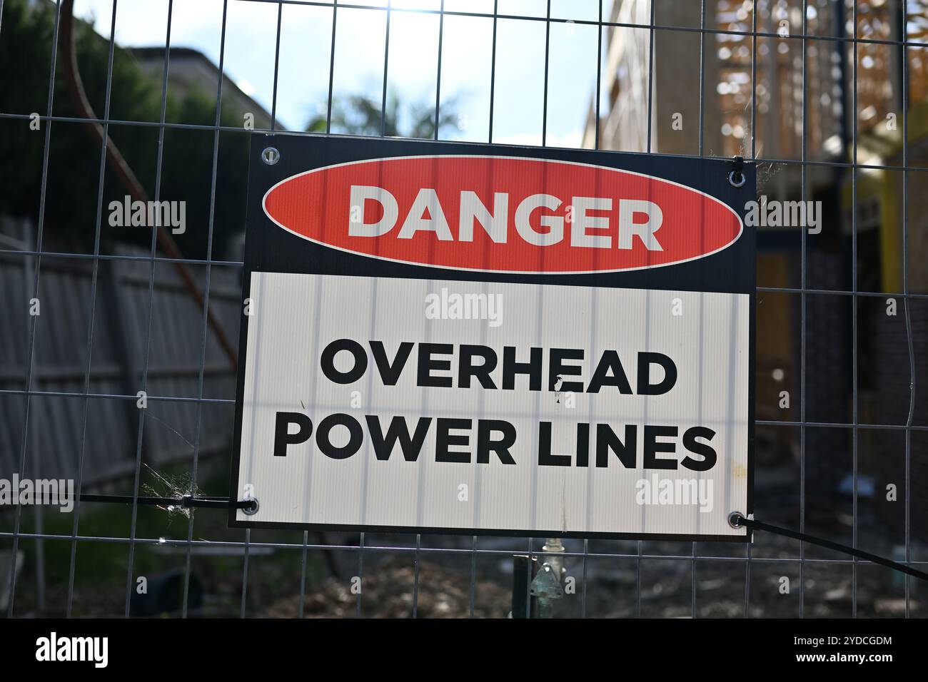 Rectangular danger overhead power lines sign attached to a tilting ...